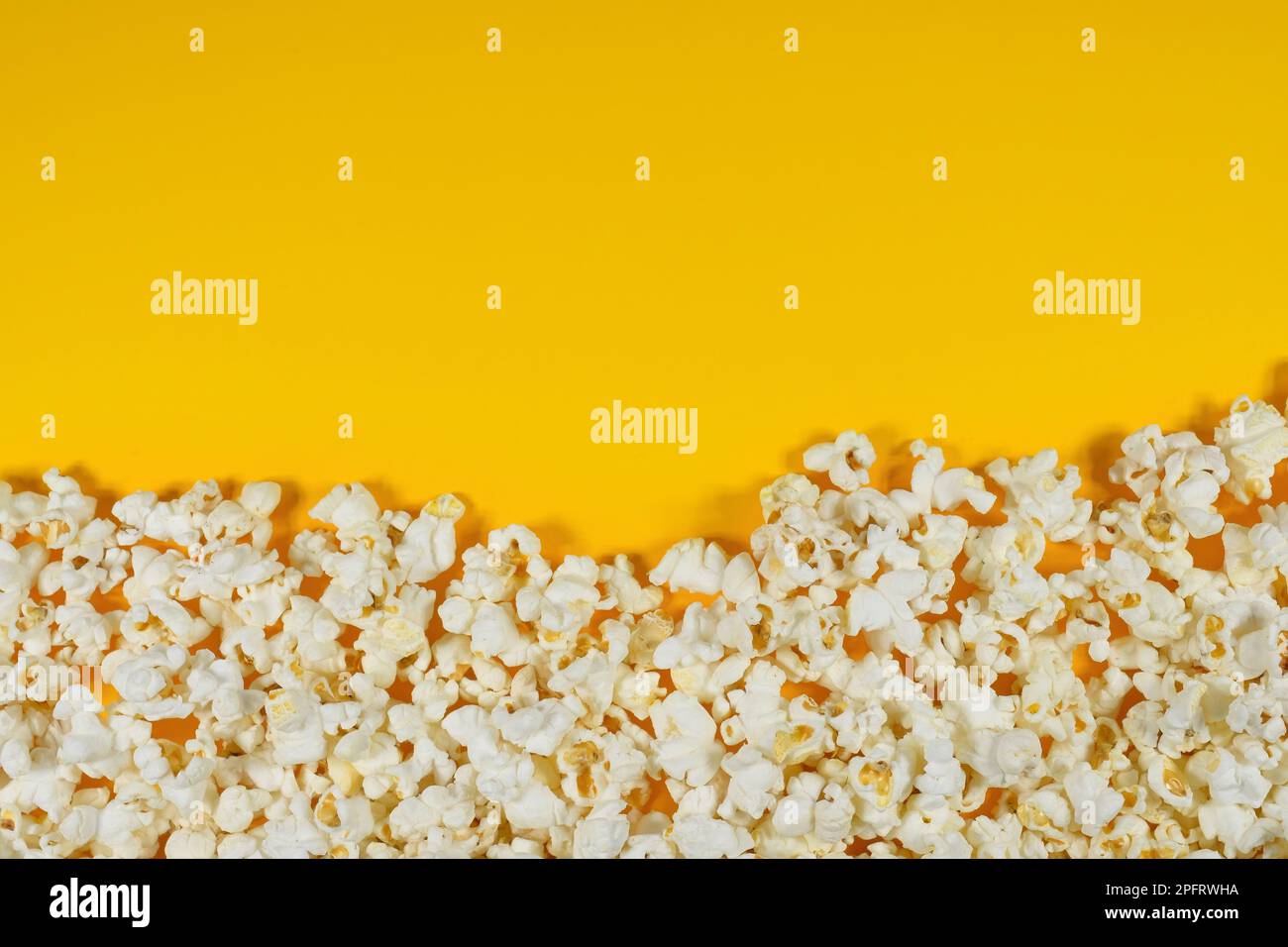 Fresh popcorn on a yellow background with copy space. Top view. Cinema ...