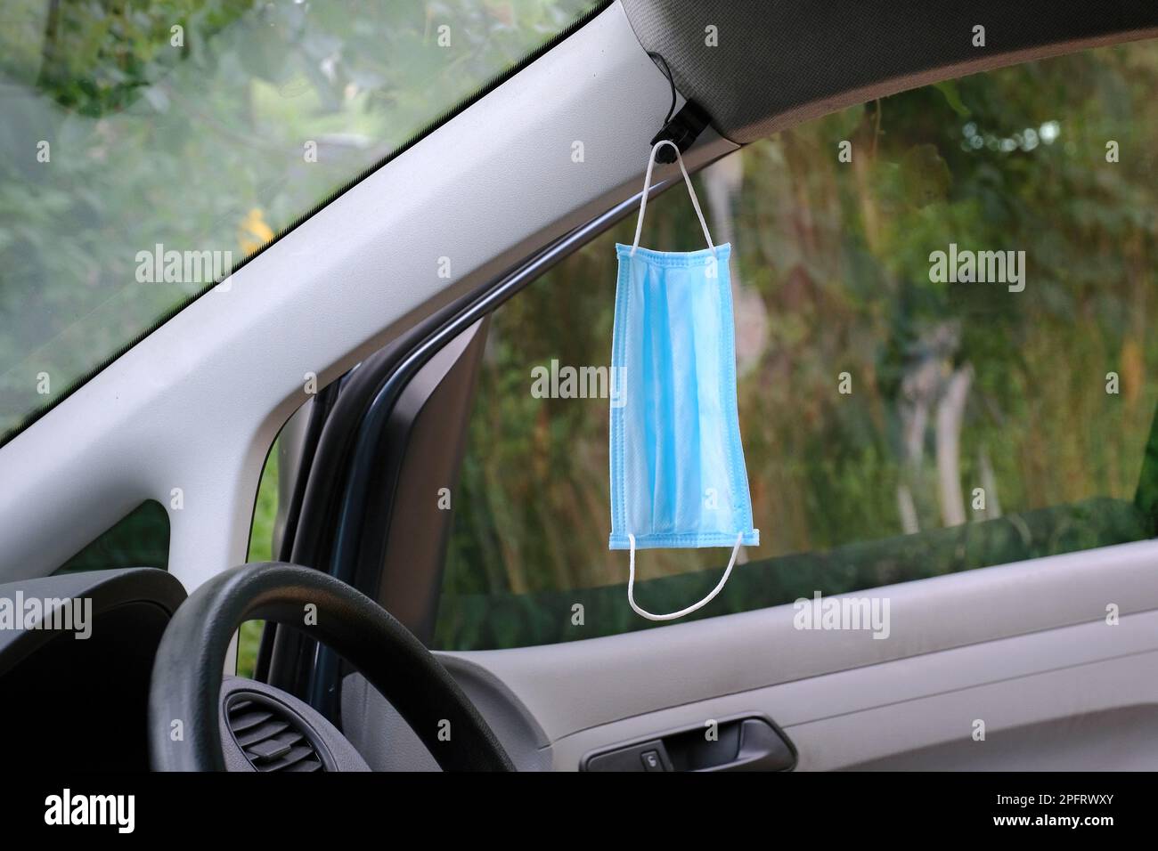 A medical protective mask hangs on the car mirror to protect against ...