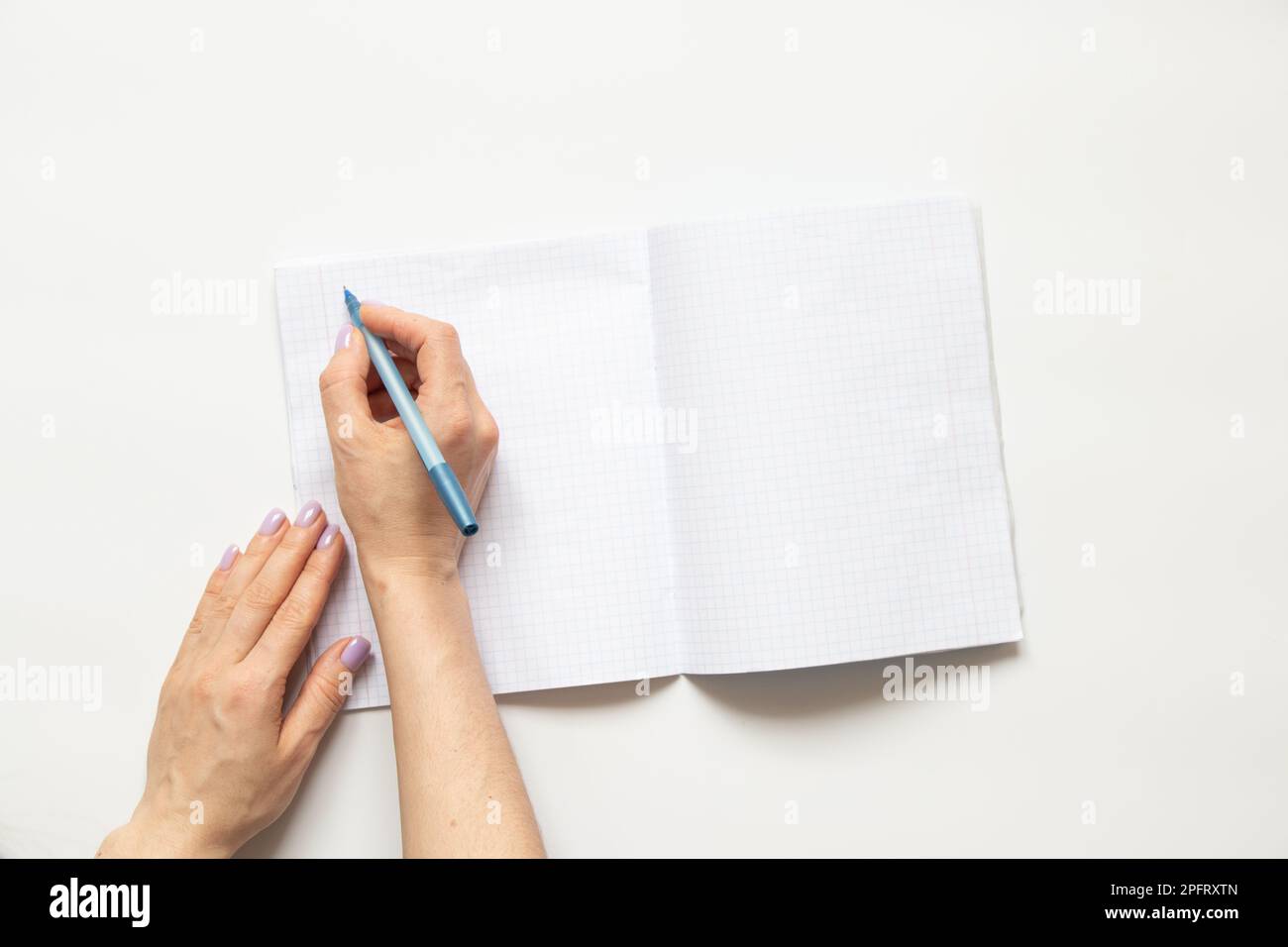 Female hands write in a notebook in a cage on a white background, blank ...