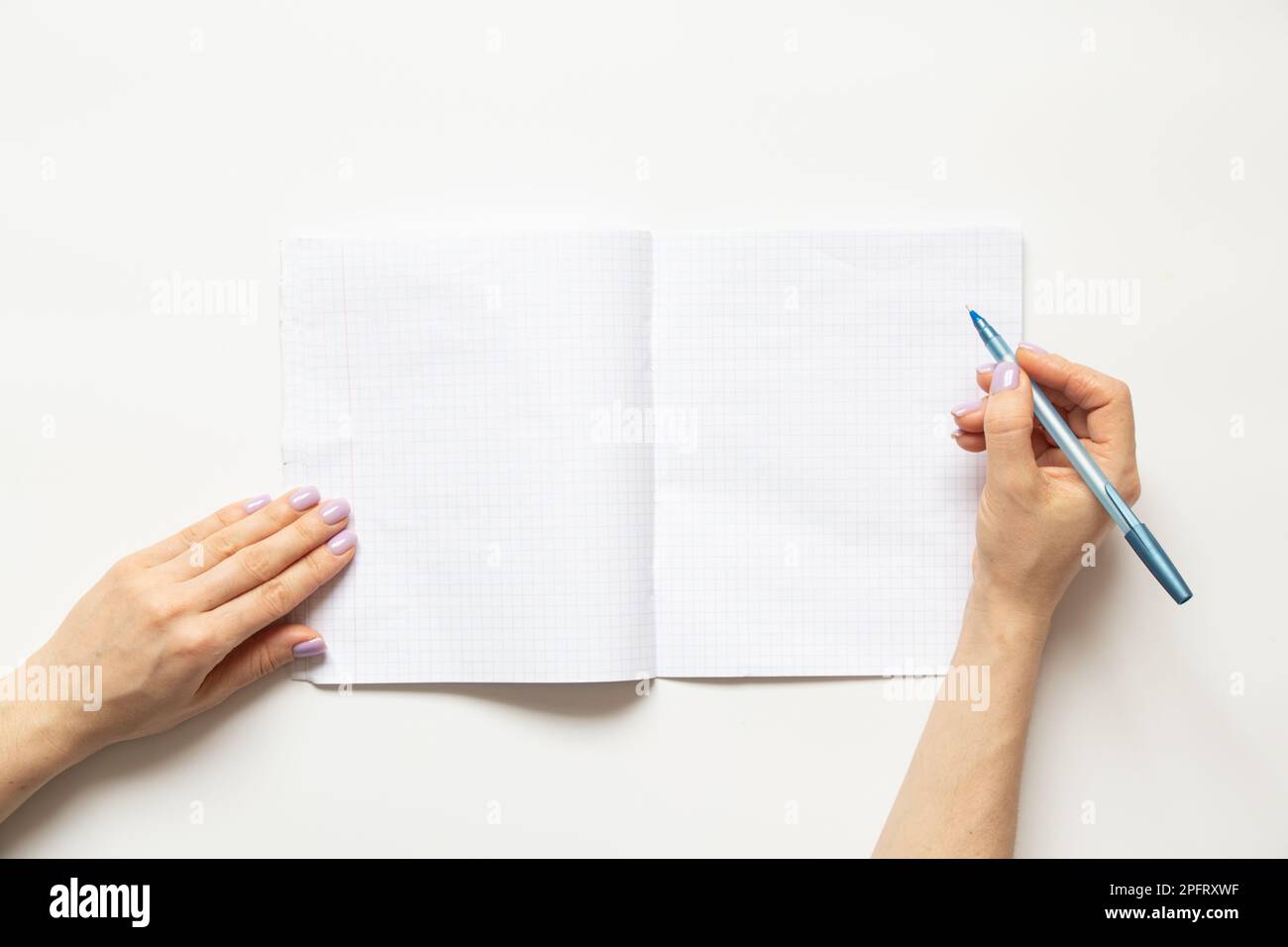 Female hands write in a notebook in a cage on a white background, blank ...