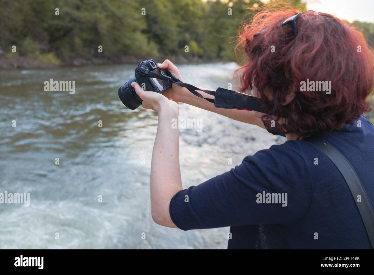 Female photographer holding mirrorless camera making outdoors photos ...