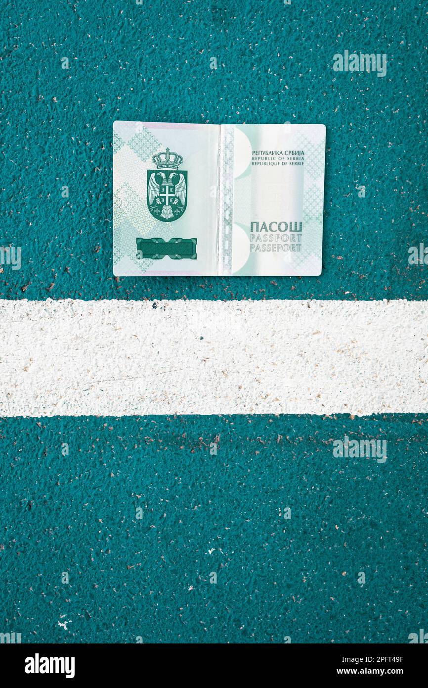Open national Serbian passport next to a white line on the ground ...