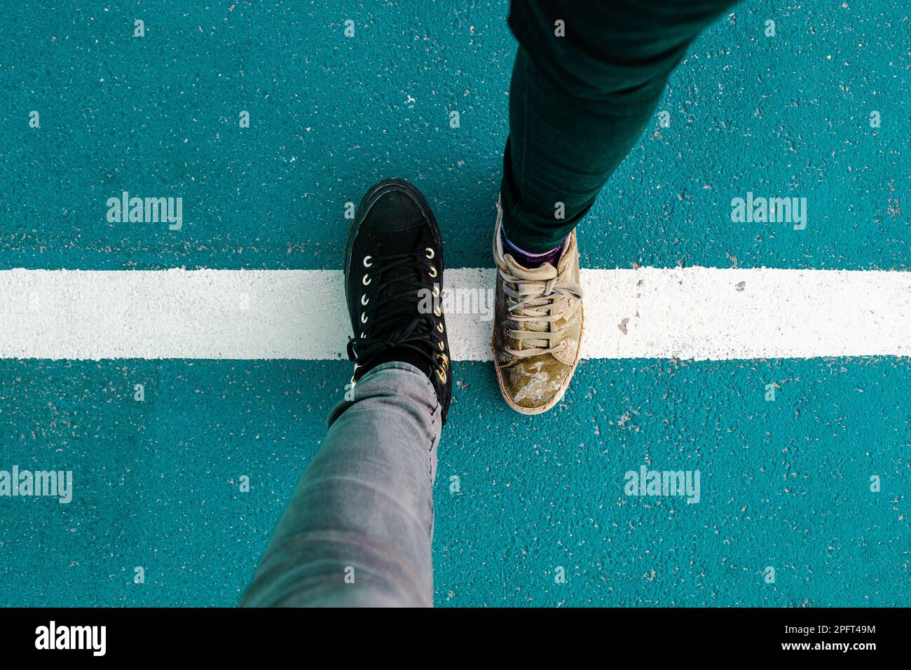 Two people foot standing on a white line on the ground. Border crossing ...