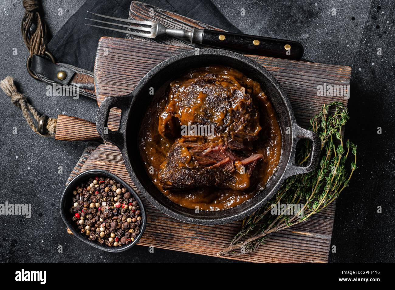 Stewed beef cheeks with brown red wine sauce in skillet. Black ...