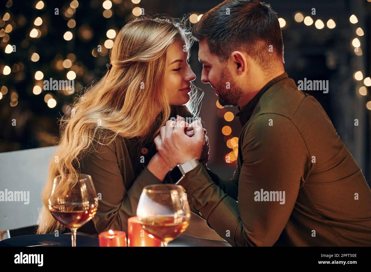 Side view. Young lovely couple have romantic dinner indoors together ...