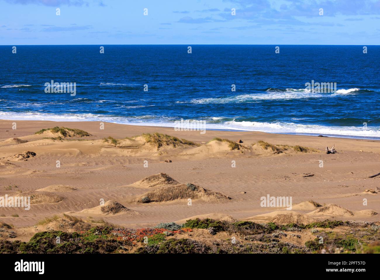 Small waves break on deserted sandy beach with blue water to the ...