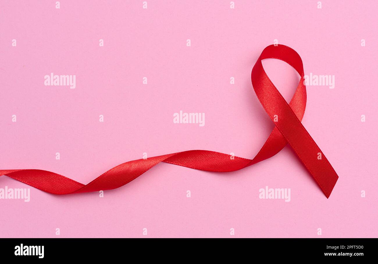 A silk red ribbon in the form of a bow on a pink background, a symbol ...