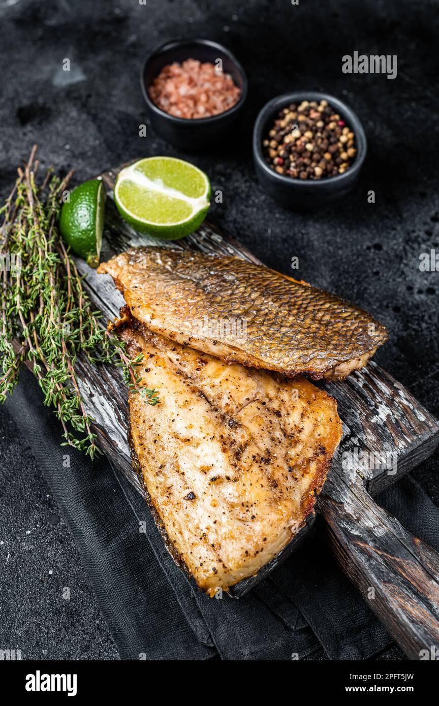 Roast Gilthead Sea Bream fillets with herbs on wooden board. Black ...