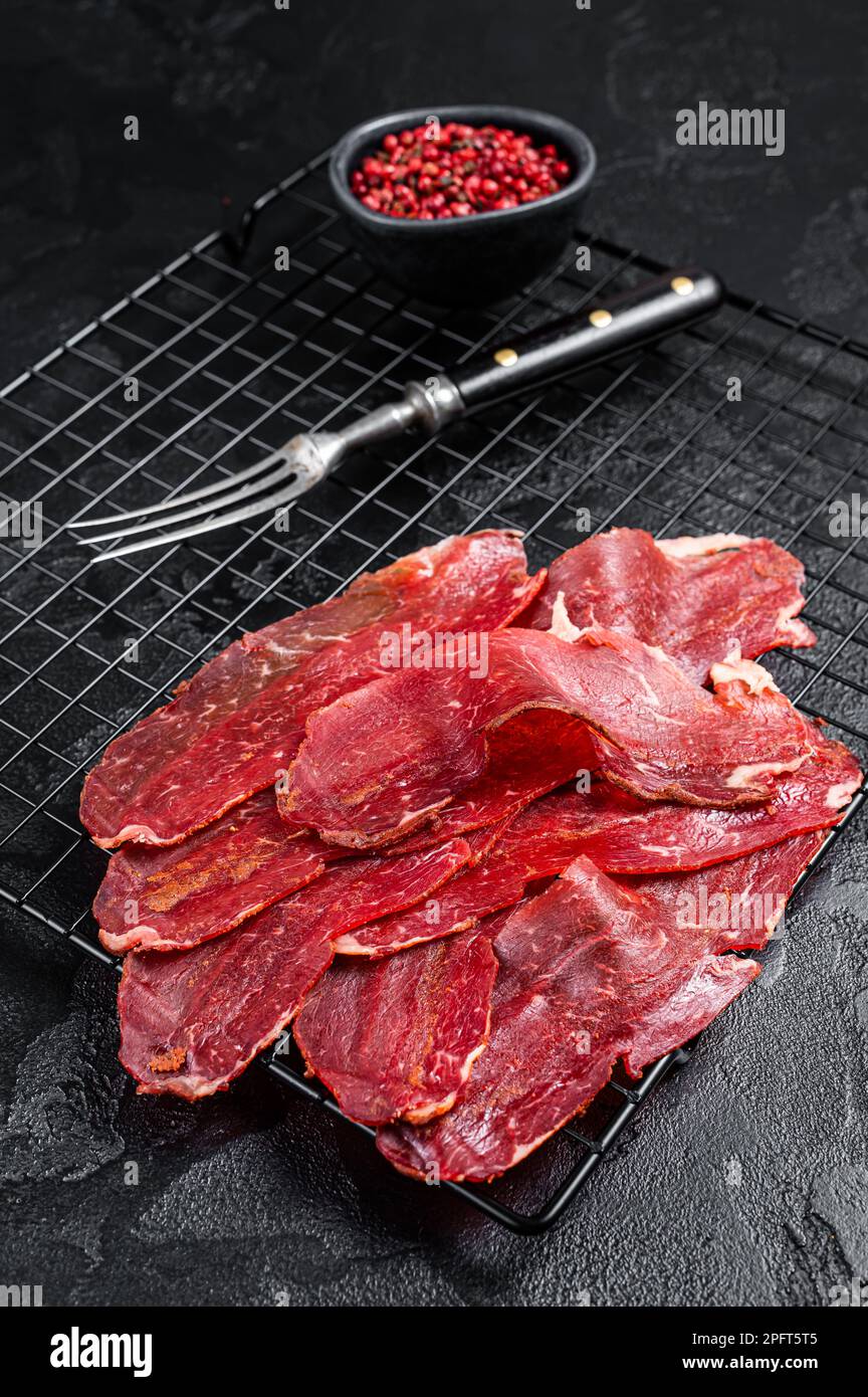 Dried sliced basturma, cured beef meat ready for eat. Black background ...