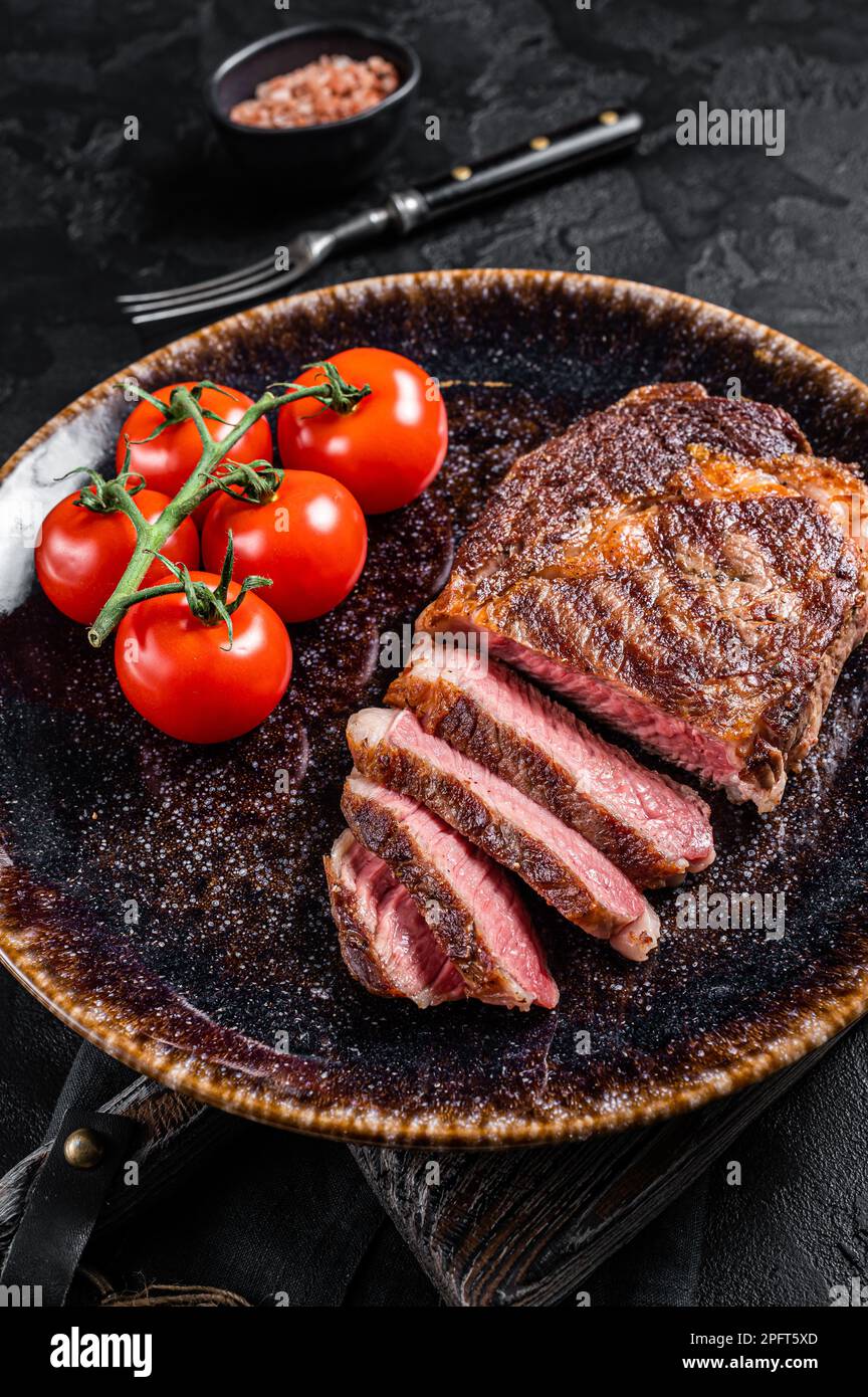 Grilled rib eye steak, ribeye beef marbled meat on a plate with tomato ...