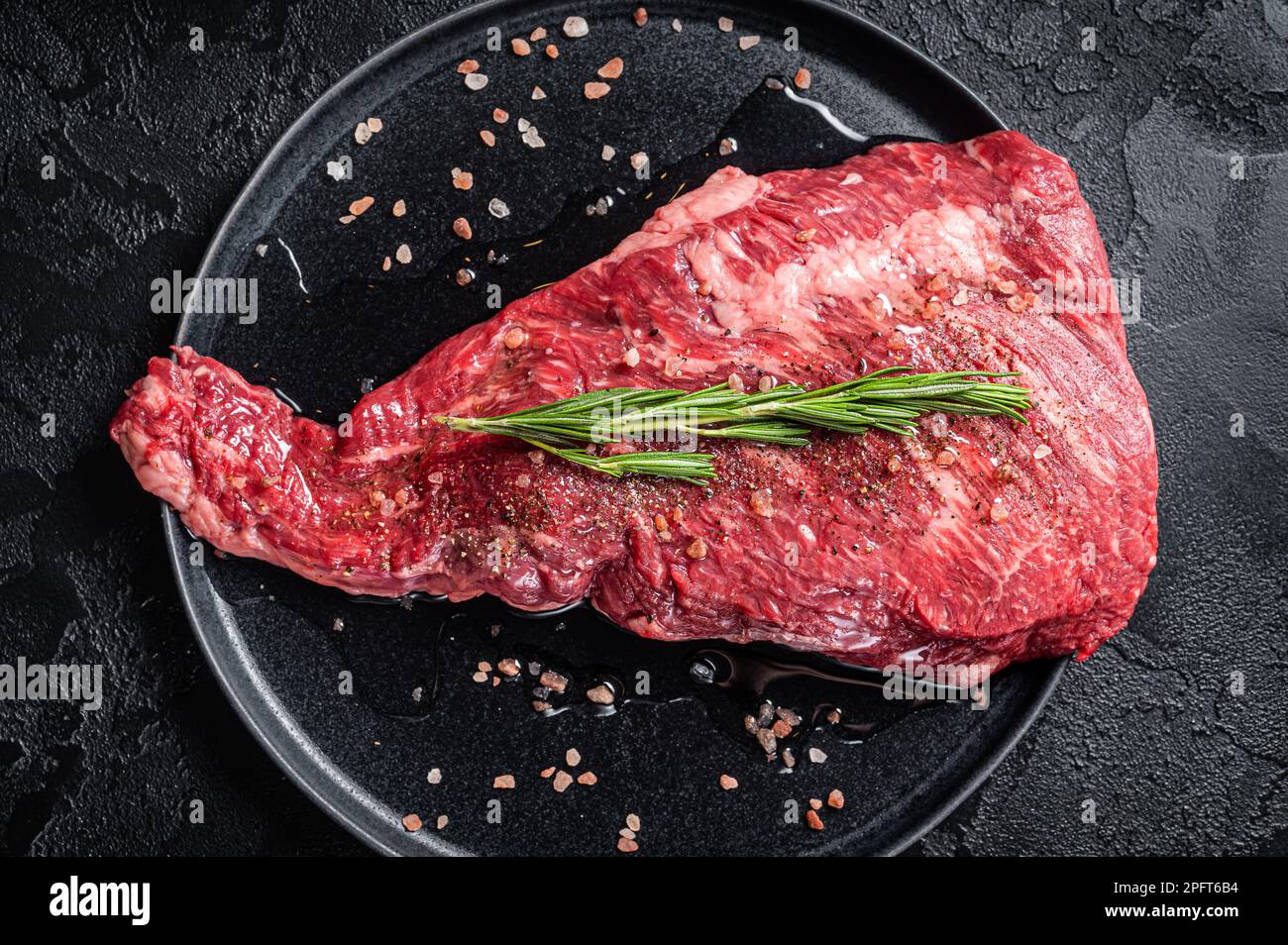 Seasoned raw tri-tip beef meat steak on plate. Black background. Top ...