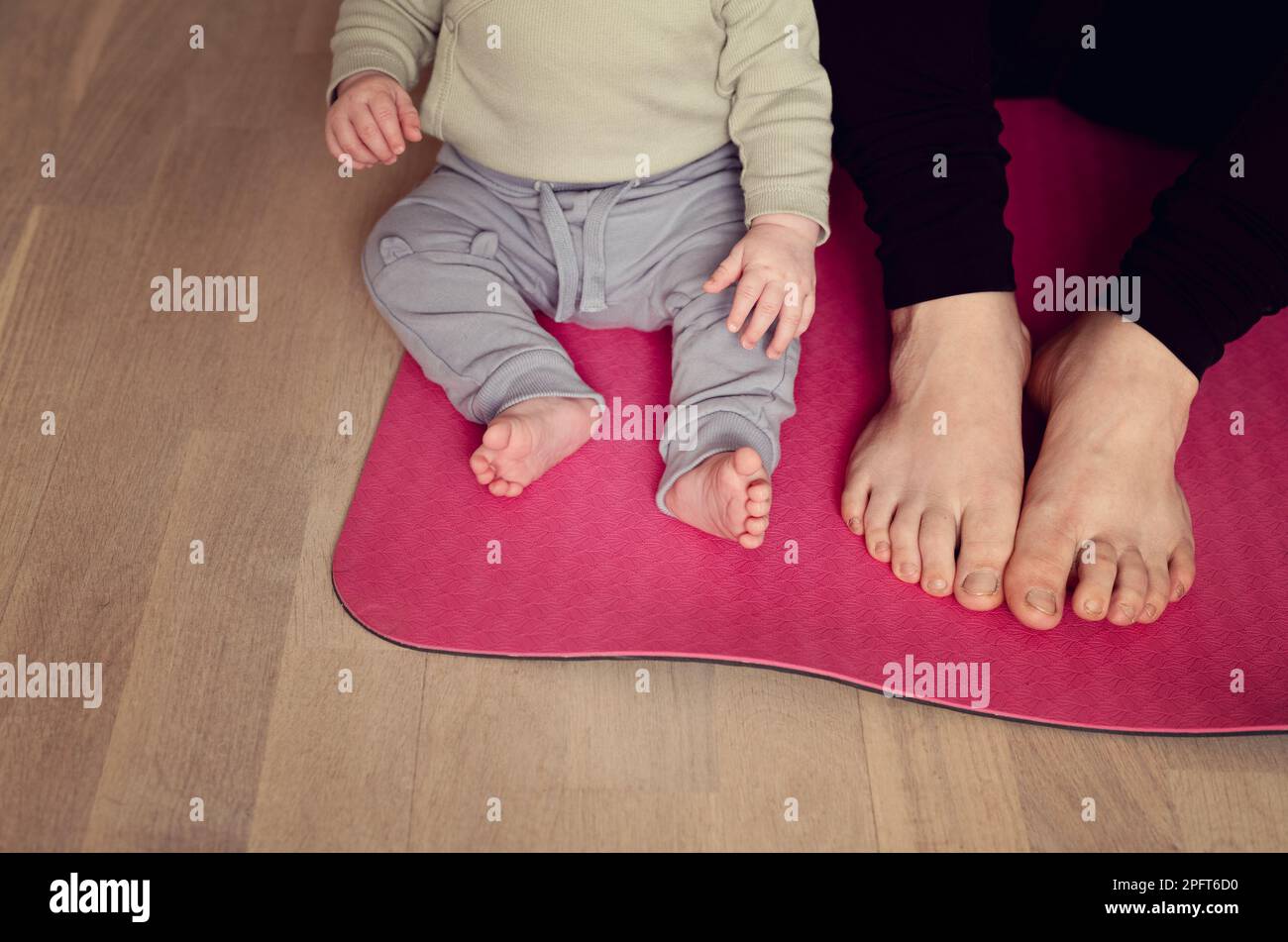 Baby and woman feet on yoga mat. Concept of postpartum exercise, workout with baby or toddler ...