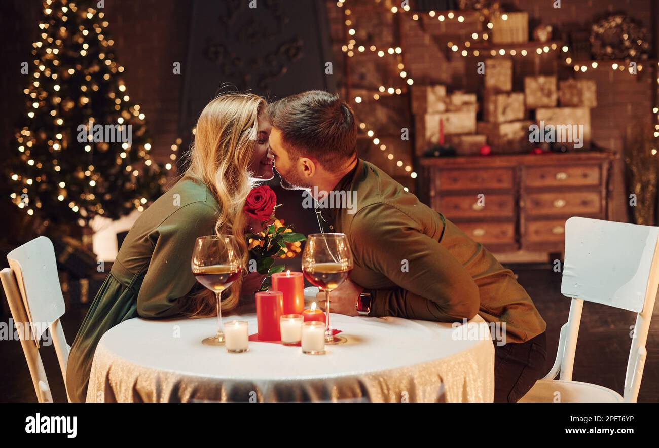 Holding beautiful red rose. Young lovely couple have romantic dinner ...