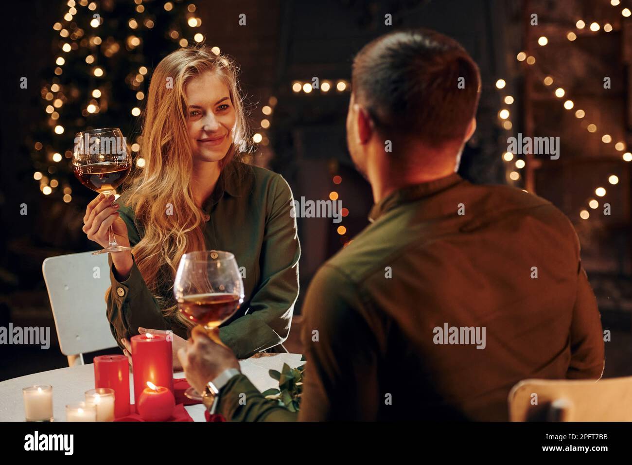 Sitting by the table. Young lovely couple have romantic dinner indoors ...