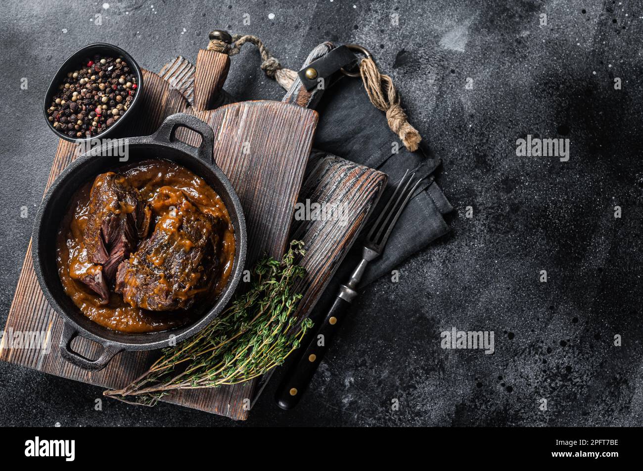 Stewed beef cheeks with brown red wine sauce in skillet. Black ...