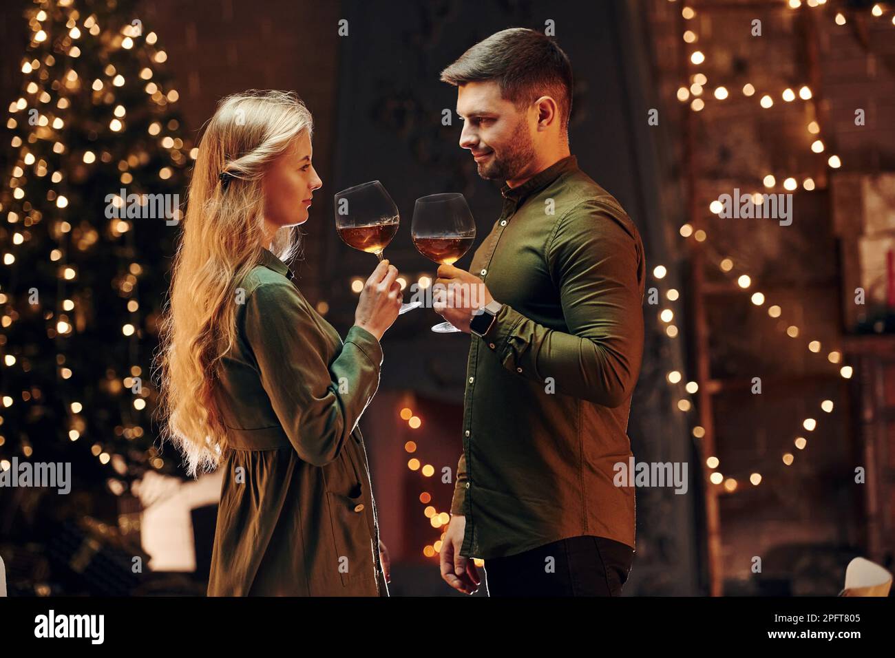 Standing And Holding Big Glasses With Wine Young Lovely Couple Have Romantic Dinner Indoors