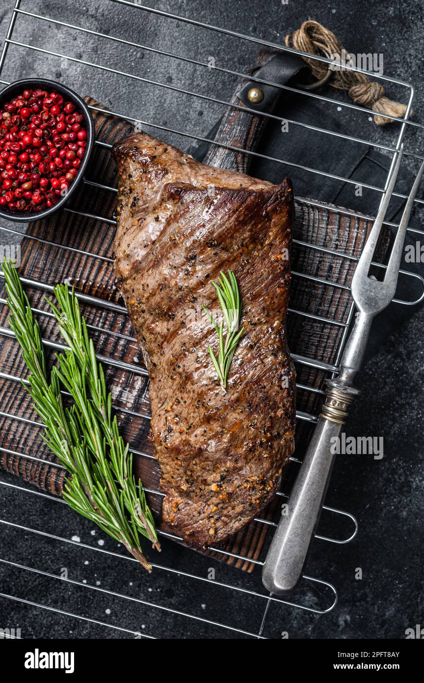 BBQ grilled tri tip beef steak on a grill. Black background. Top view ...