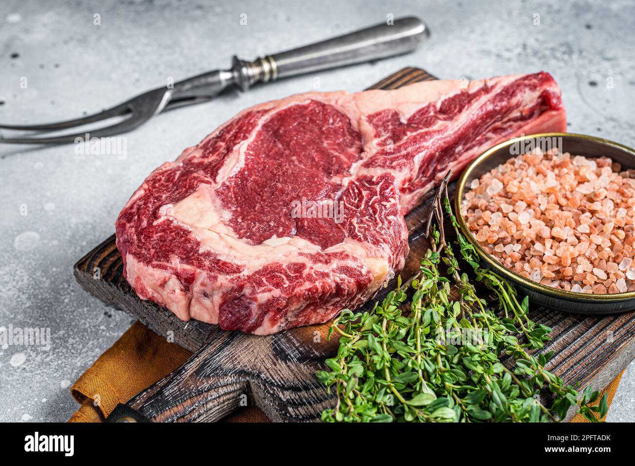 Raw uncooked black angus beef cowboy or rib eye steak. Gray background ...