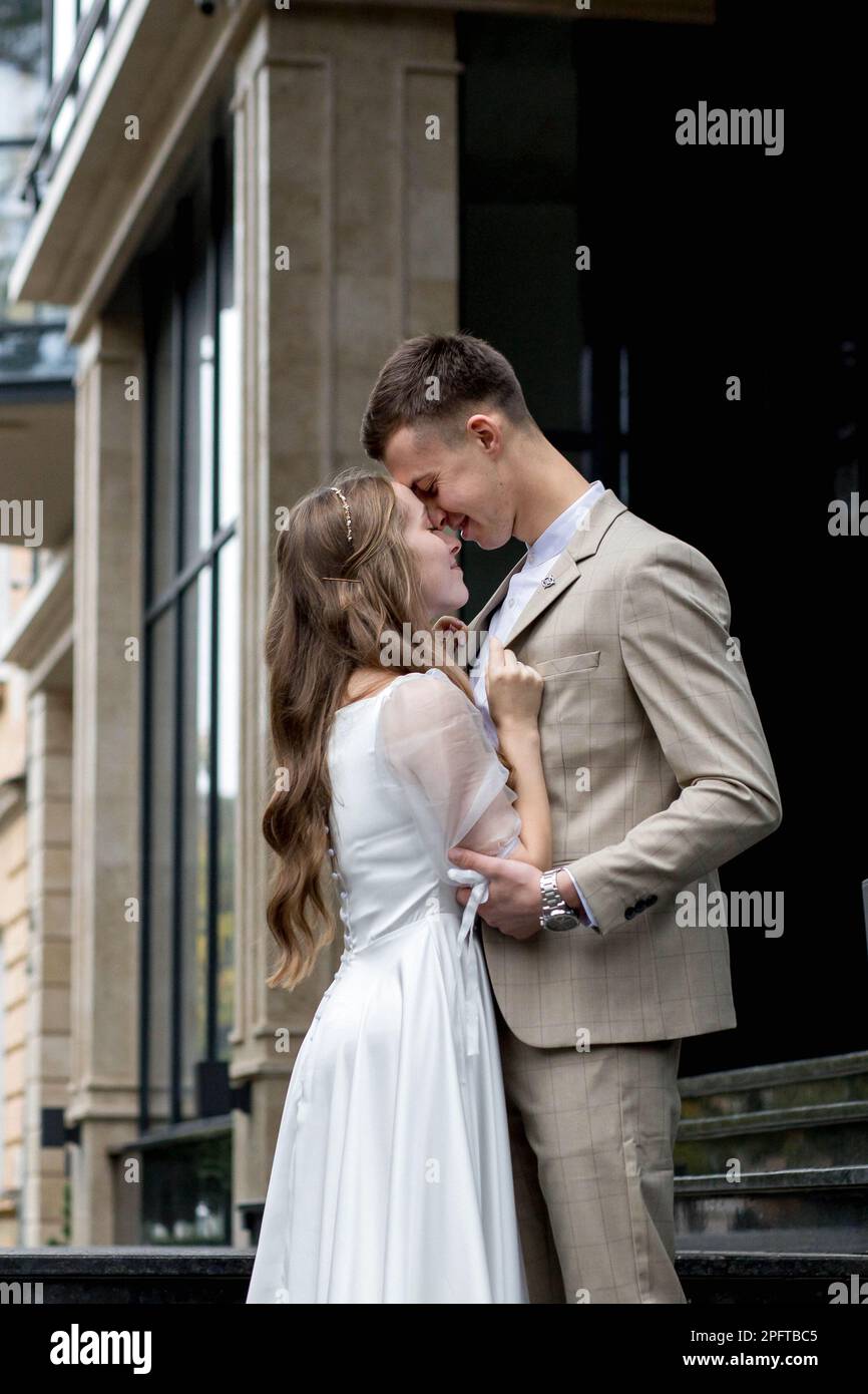 The bride looks at the groom with loving eyes. Smiling newlyweds look ...