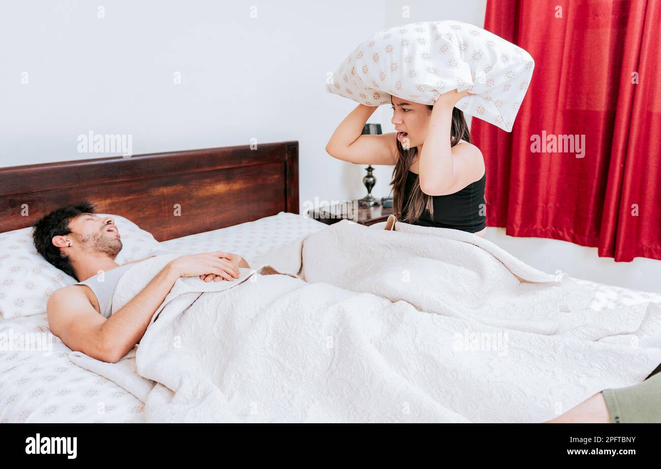 Suffering wife covering her ears while her husband snores. Angry woman ...