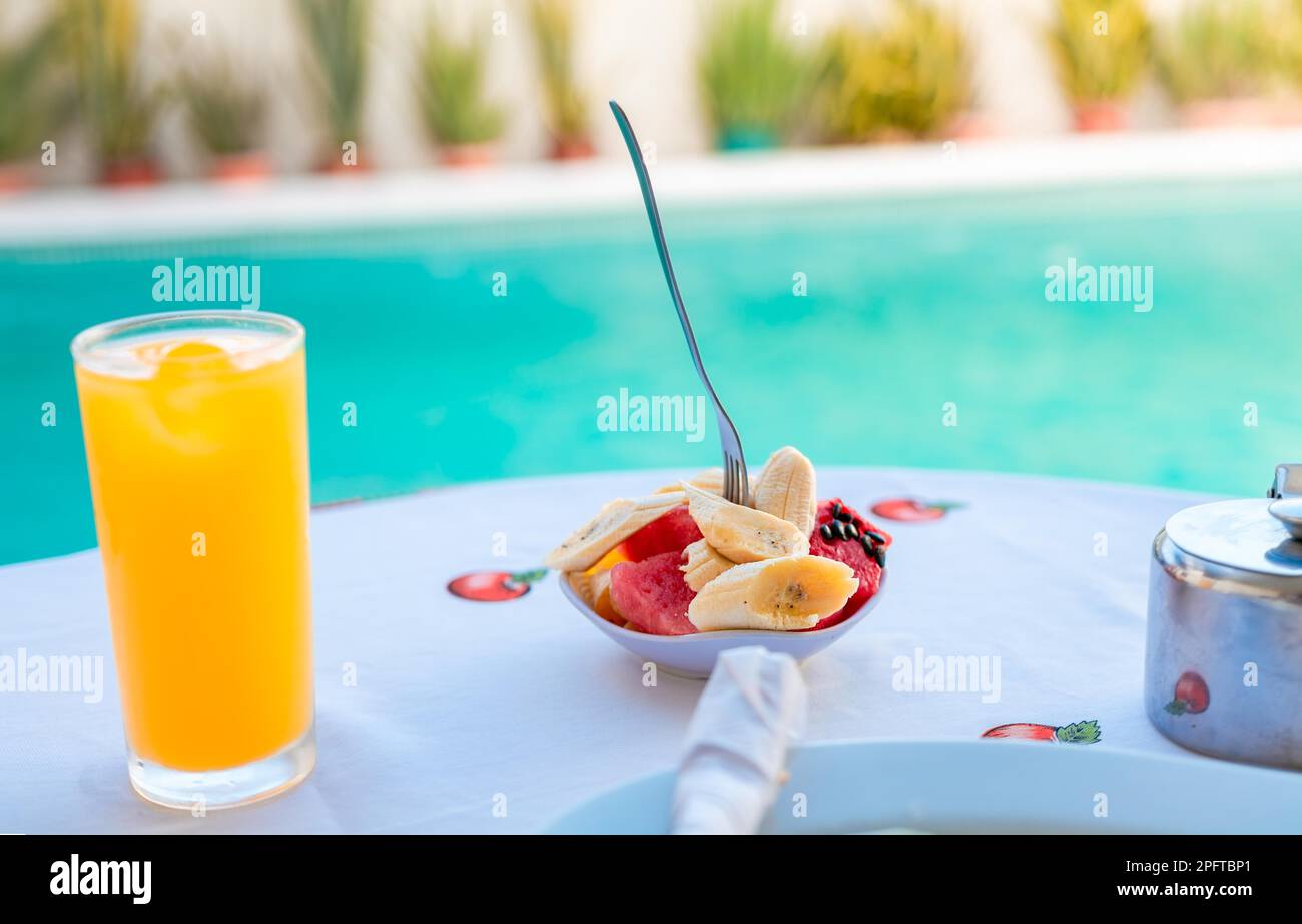 Breakfast fruit salad with swimming pool in the background. Fruit salad ...