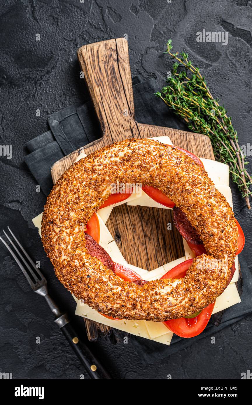 Simit bagel sandwich with lettuce, tomato, yellow cheese and ham. Black ...