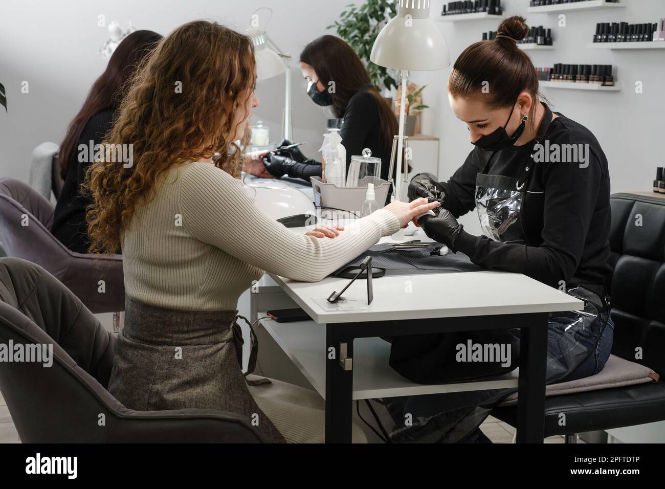 Doing manicure in salon. Female manicurist working on client nails in ...