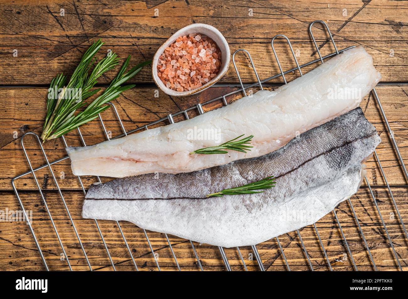 Raw fish fillets on grill with rosemary and herbs. Wooden background ...
