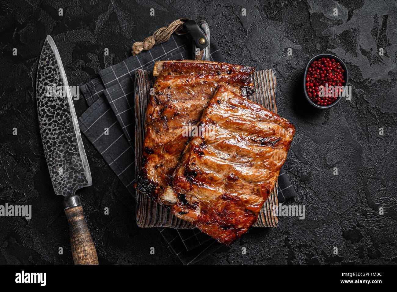 Stack of grilled pork ribs in BBQ sauce on a chopping board. Black ...
