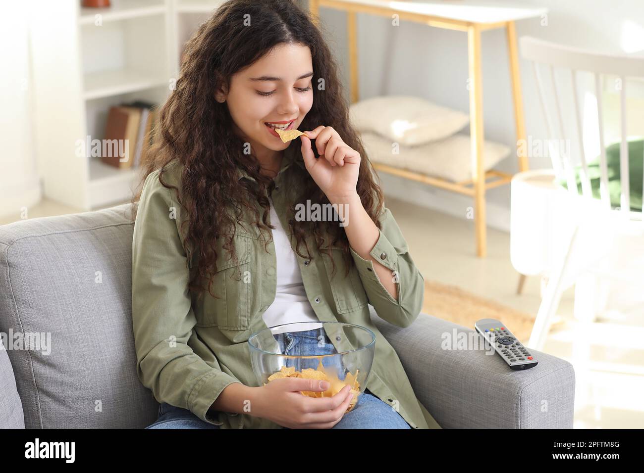 Teenage girl eating tasty chips at home Stock Photo - Alamy