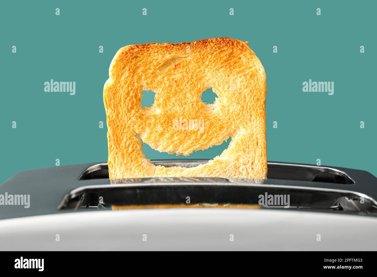 Funny slice of bread in modern toaster on green background Stock Photo ...