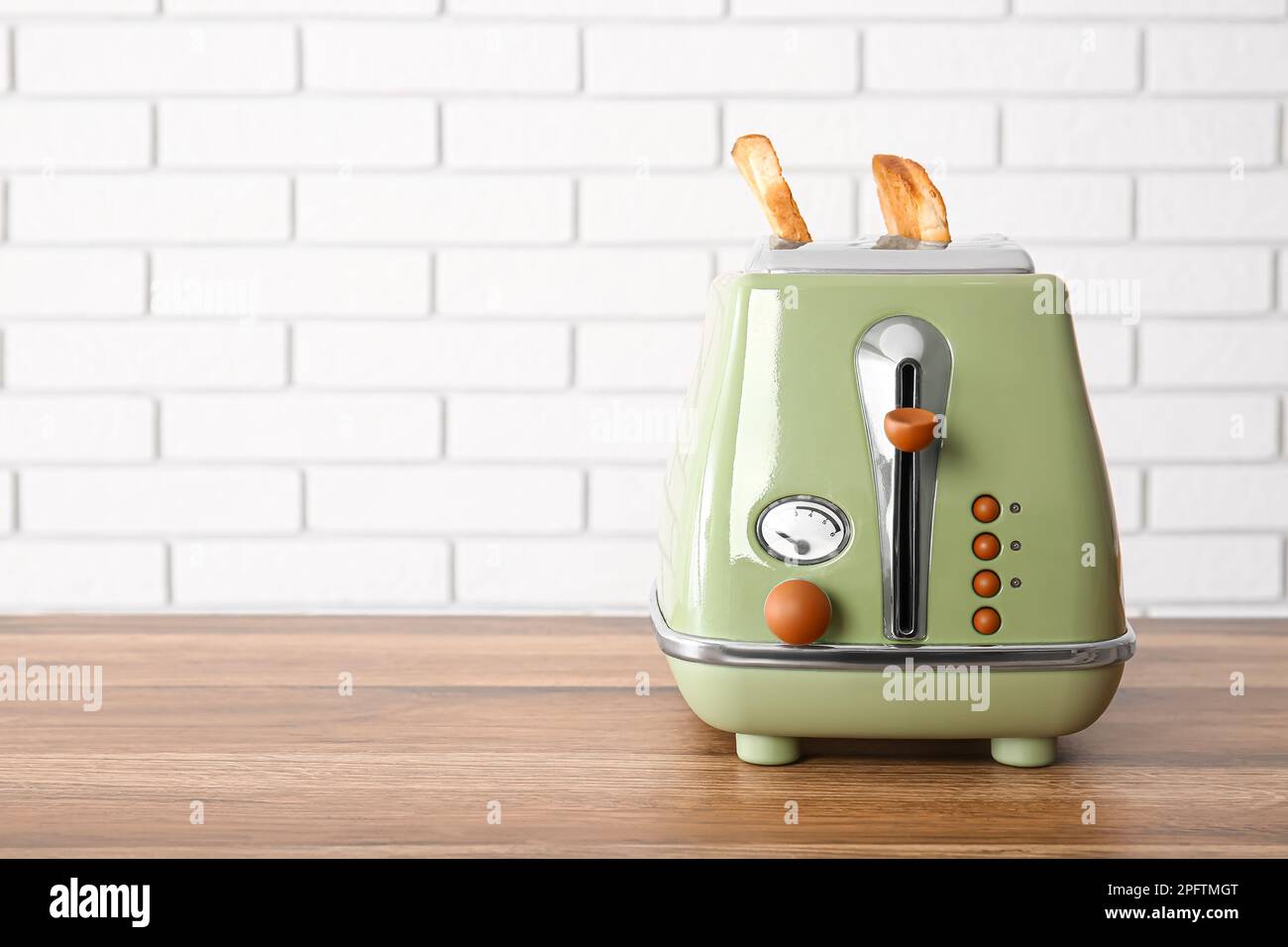 Modern toaster with crispy bread slices on wooden table near white brick wall Stock Photo - Alamy
