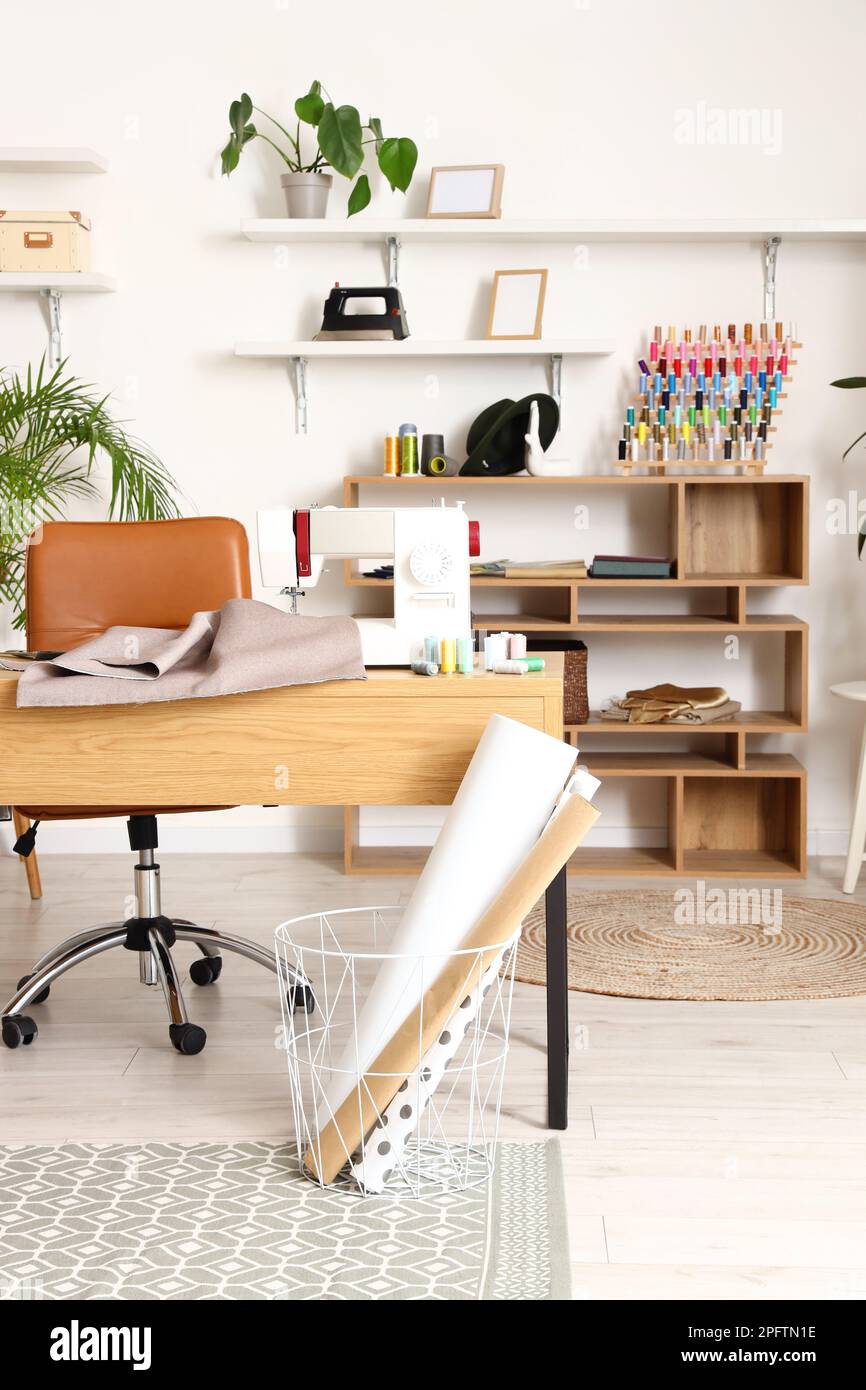 Tailor's workplace with sewing machine in interior of modern atelier ...