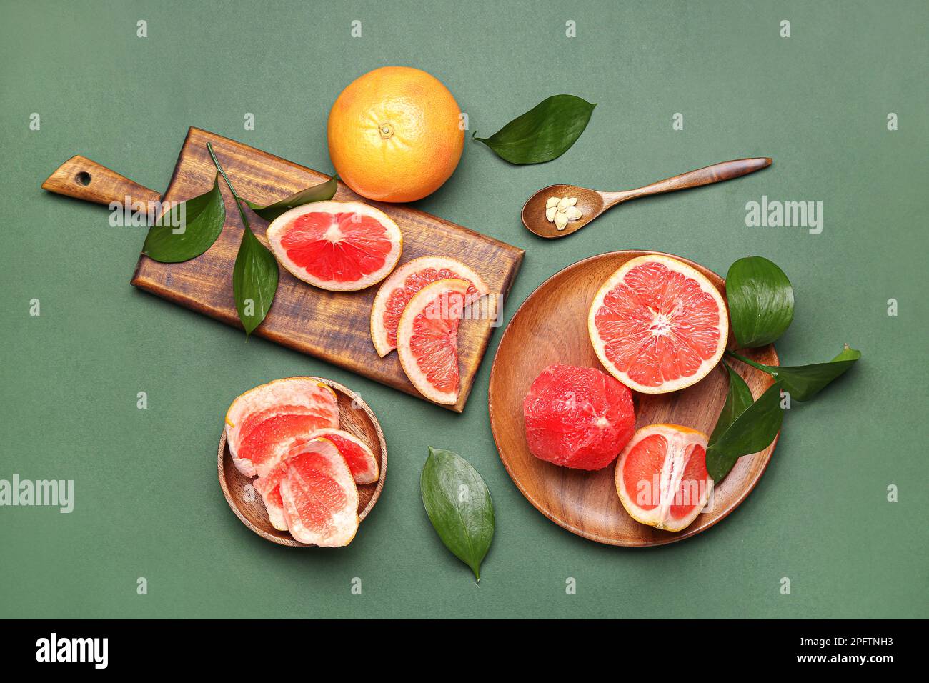 Composition with ripe grapefruits and plant leaves on green background ...