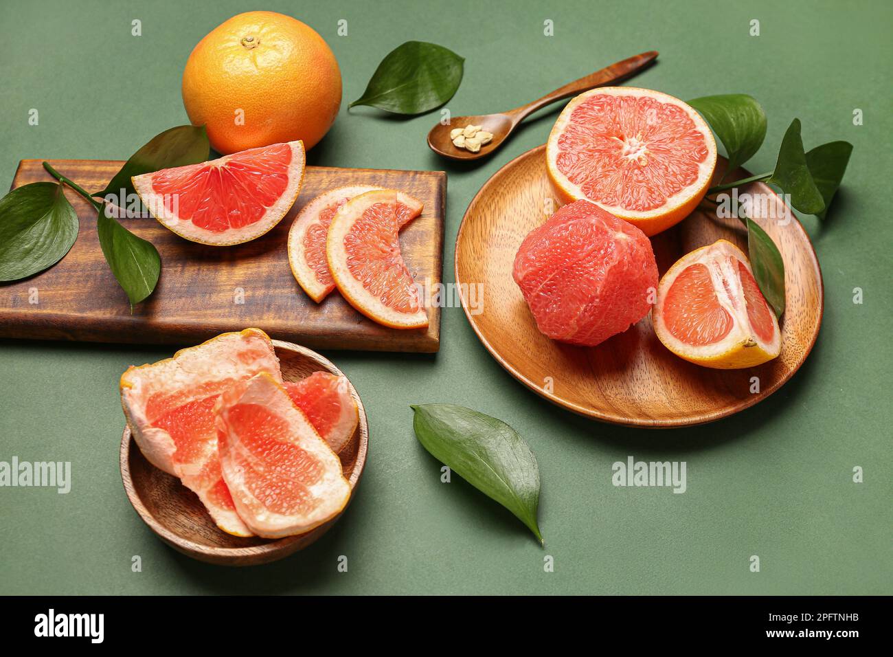 Composition with ripe grapefruits and plant leaves on green background ...