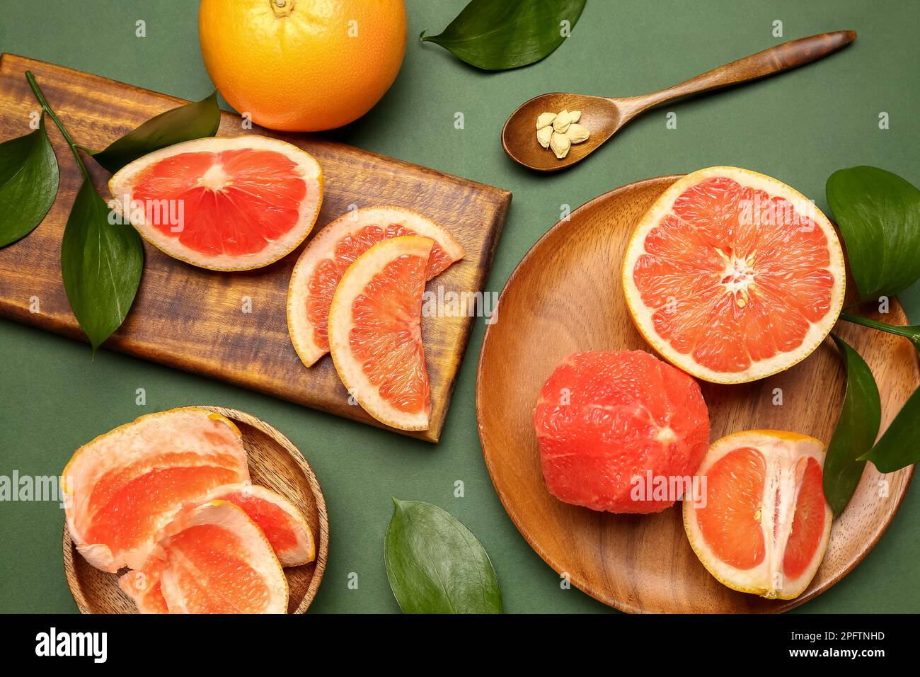 Composition with ripe grapefruits and plant leaves on green background ...