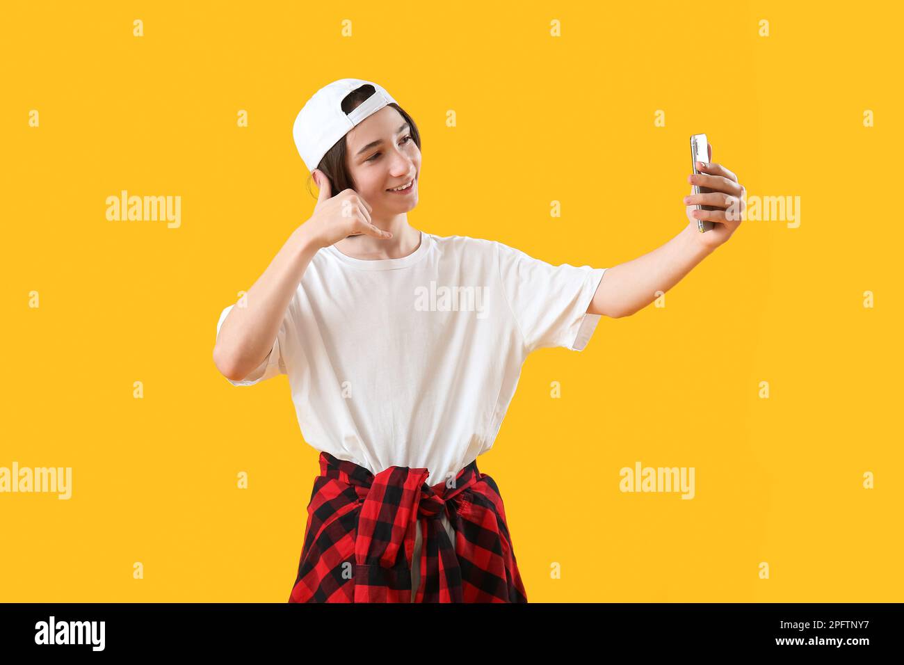 Cool teenage boy with mobile phone showing "call me" gesture on yellow ...
