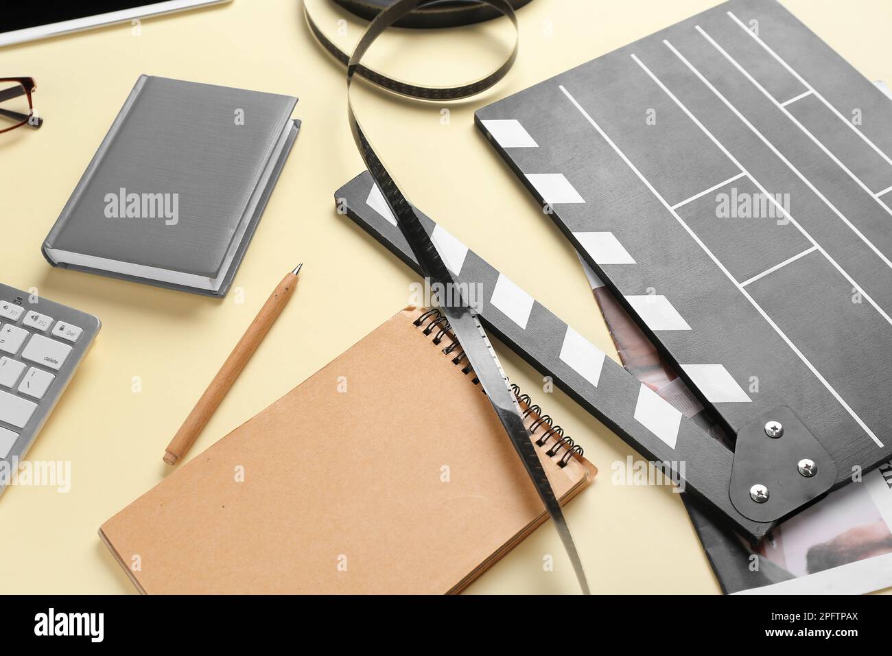 Notebooks with movie clapper and film reel on beige background, closeup ...