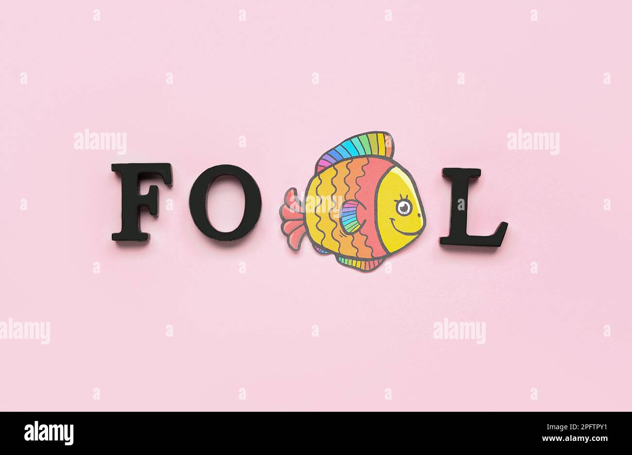 Word FOOL with paper fish on pink background Stock Photo - Alamy