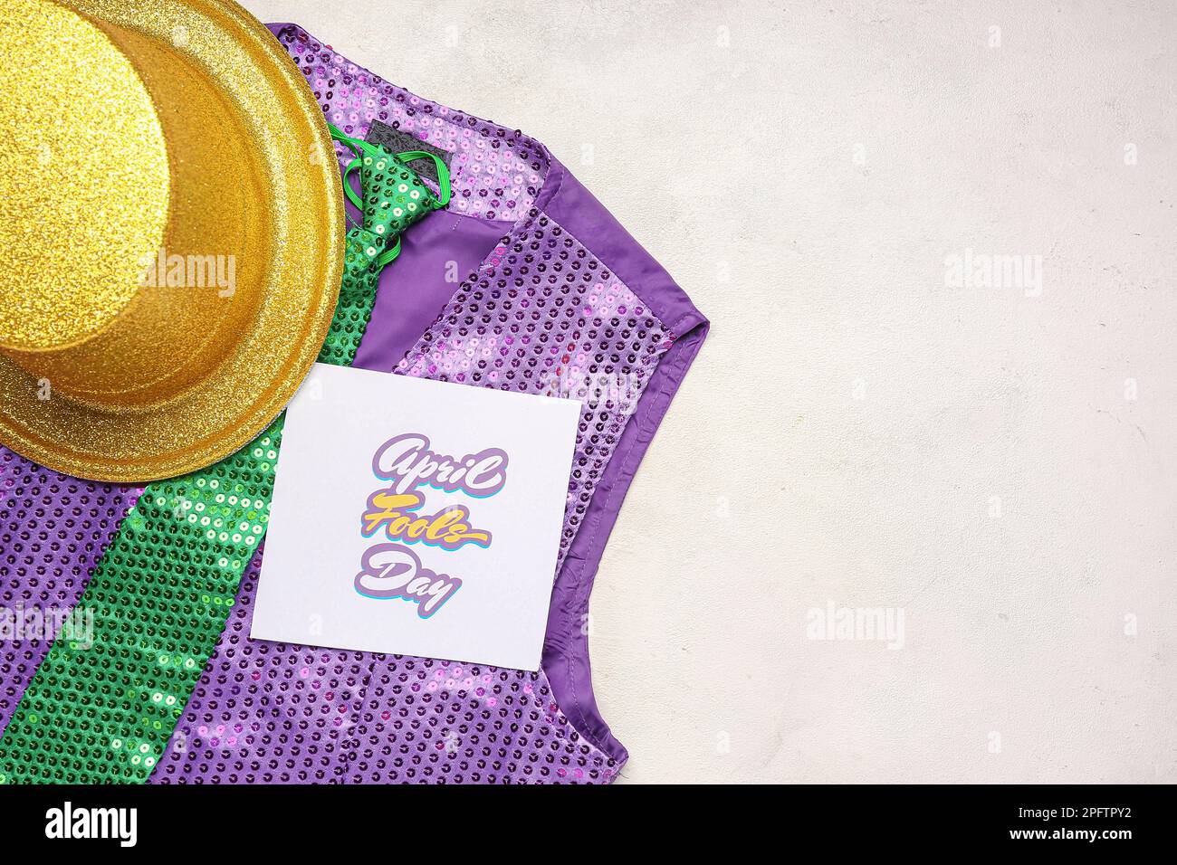 Paper with text APRIL FOOLS DAY, clothes and party hat on white ...