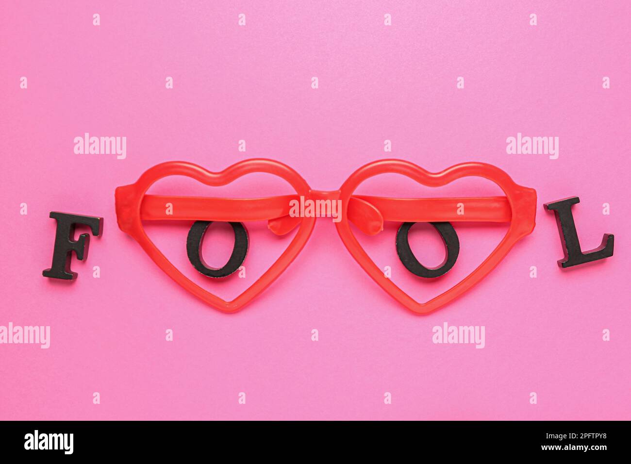Word FOOL with eyeglasses on pink background Stock Photo - Alamy