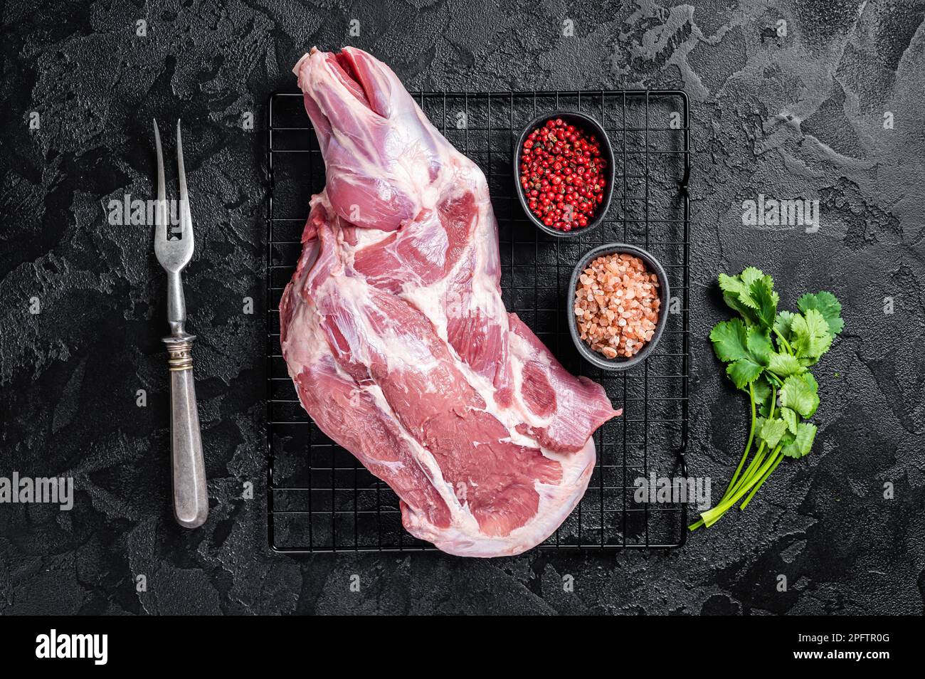 Fresh Raw lamb shoulder leg on kitchen table ready for cooking. Black ...