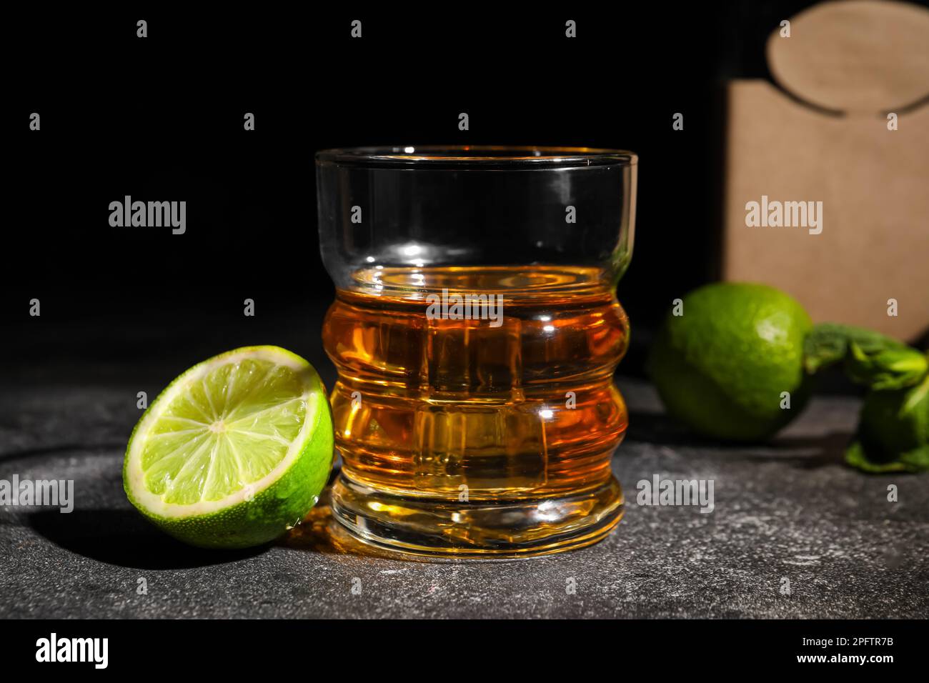 Glass of rum with ice and lime on dark table Stock Photo - Alamy