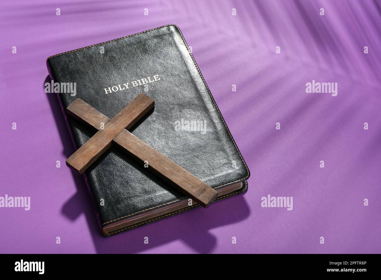 Wooden cross with Holy Bible on violet background. Good Friday concept ...