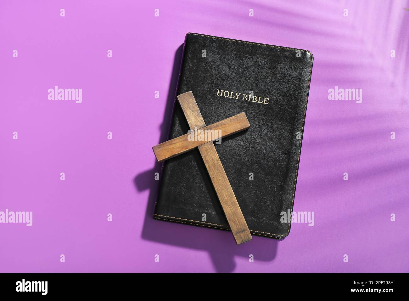 Wooden cross with Holy Bible on violet background. Good Friday concept ...