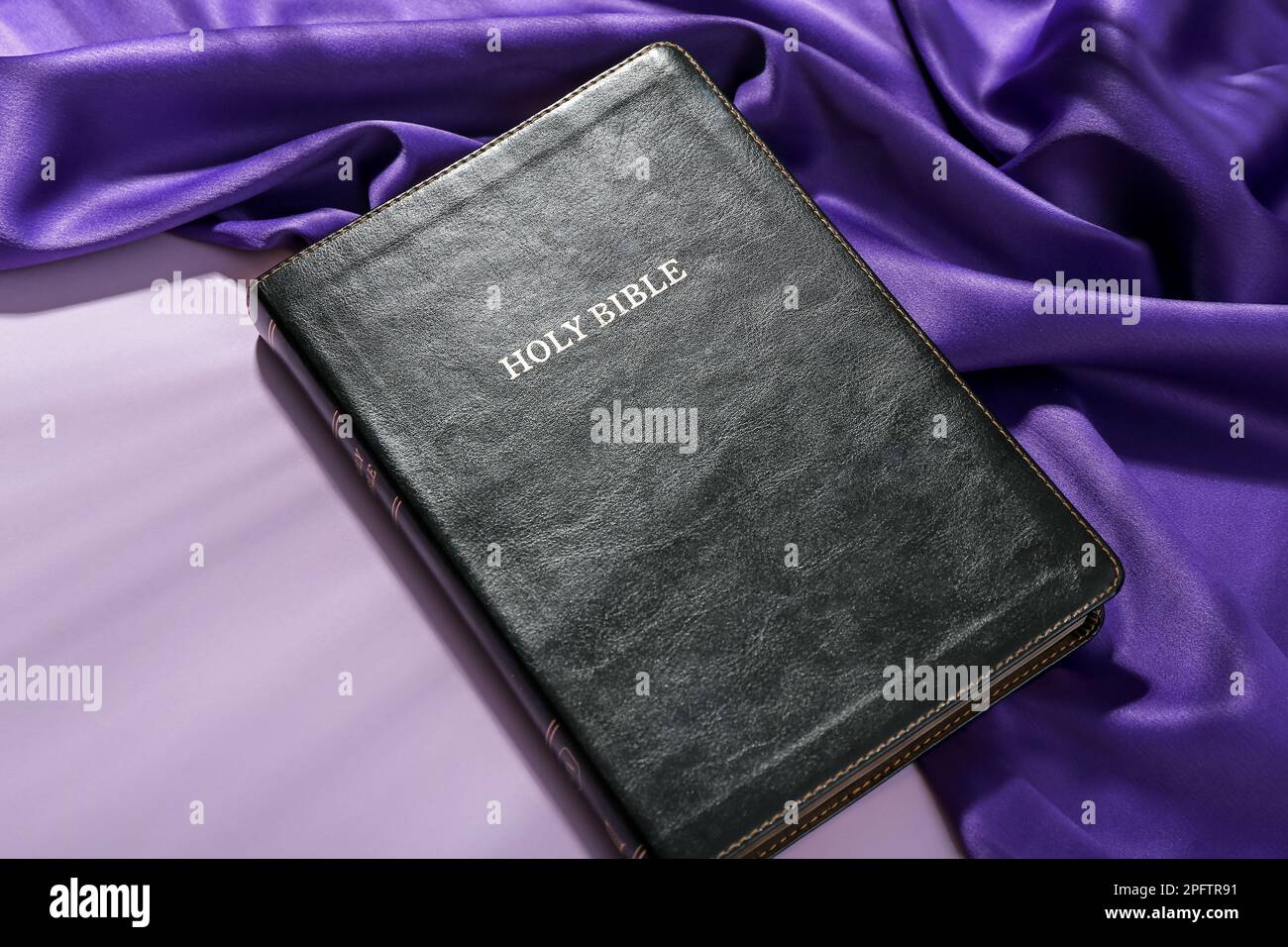 Holy Bible and purple fabric on lilac background. Good Friday concept ...