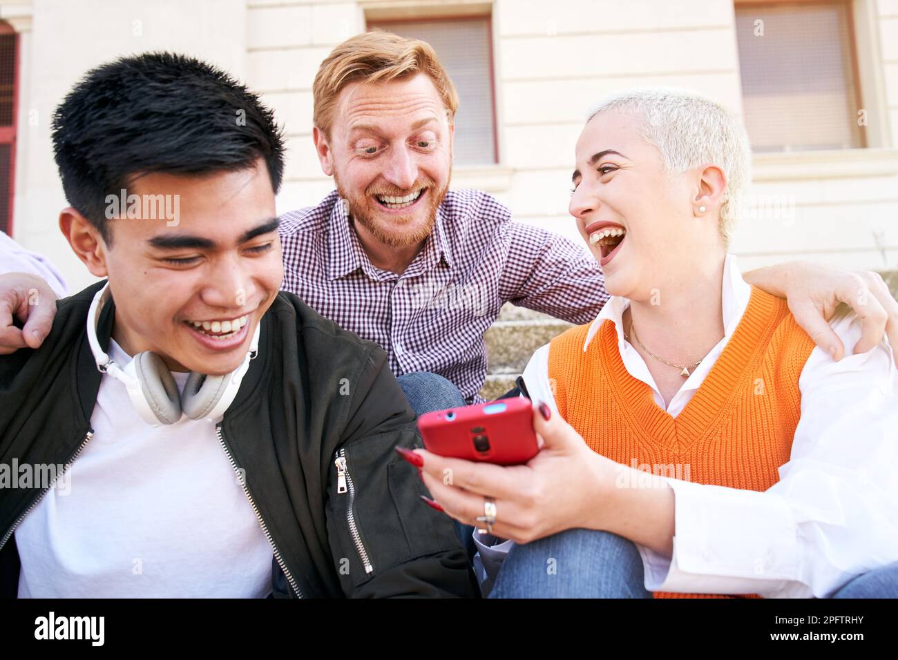 Big laugh of a woman with multiracial friends using mobile. People ...