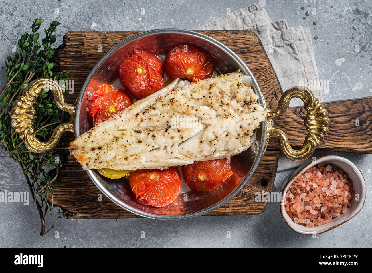 Roasted Haddock fish fillet in skillet with tomato and potato. Gray ...