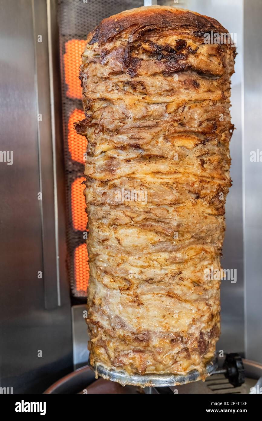 Juicy Greek traditional gyros grilled on fire and chopped by a knife ...