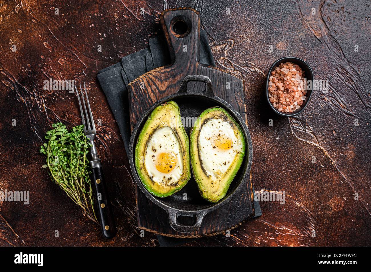 Baked Avocado with Egg, Salt, thyme and Pepper. Dark background. Top ...